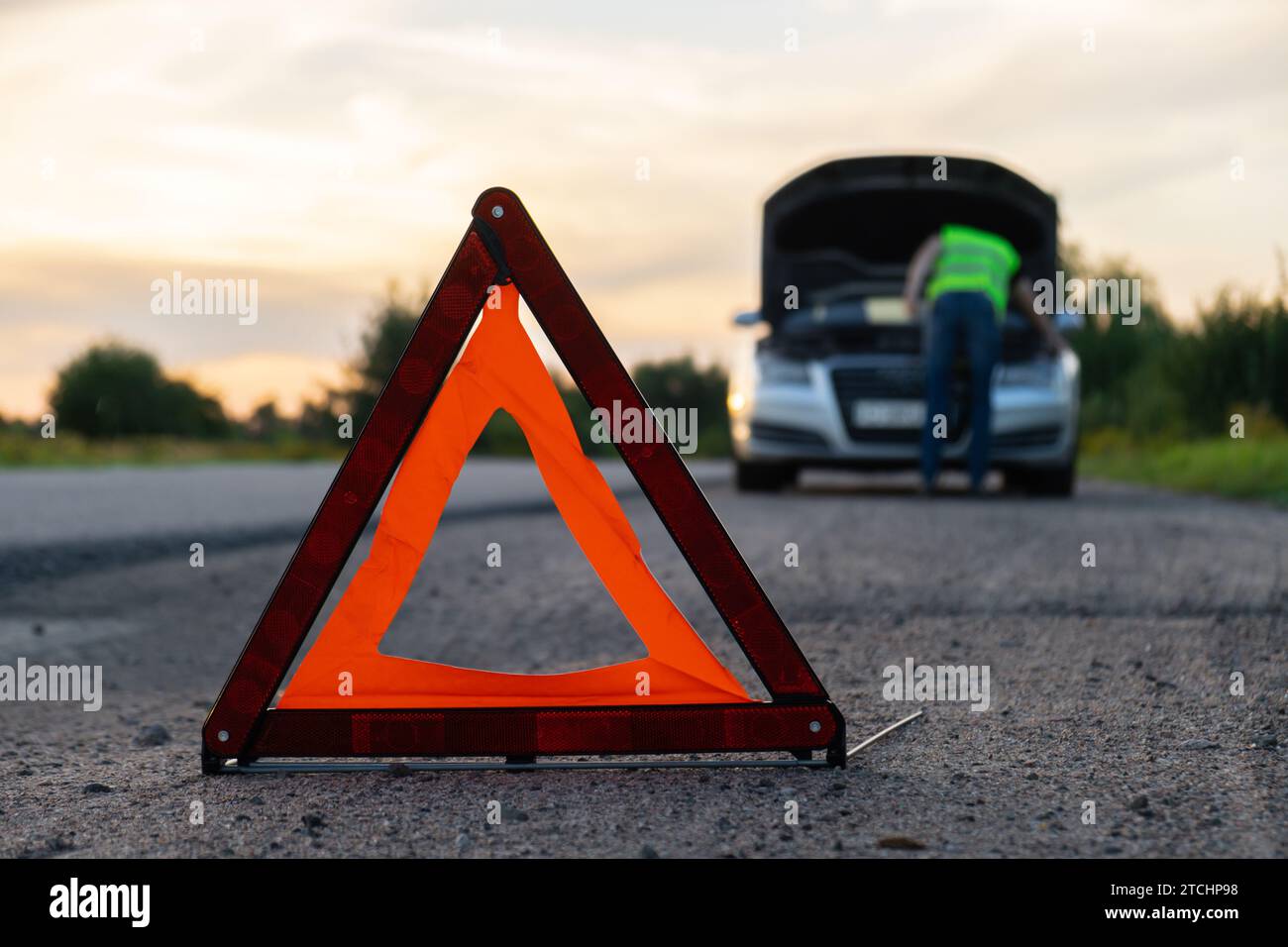 Broken silver luxury car emergency accident. Man driver installing red ...