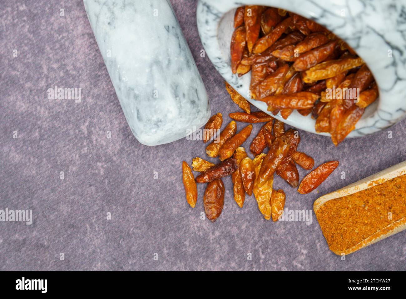 Whole cayenne pepper in a white marble mortar and ground cayenne pepper ...
