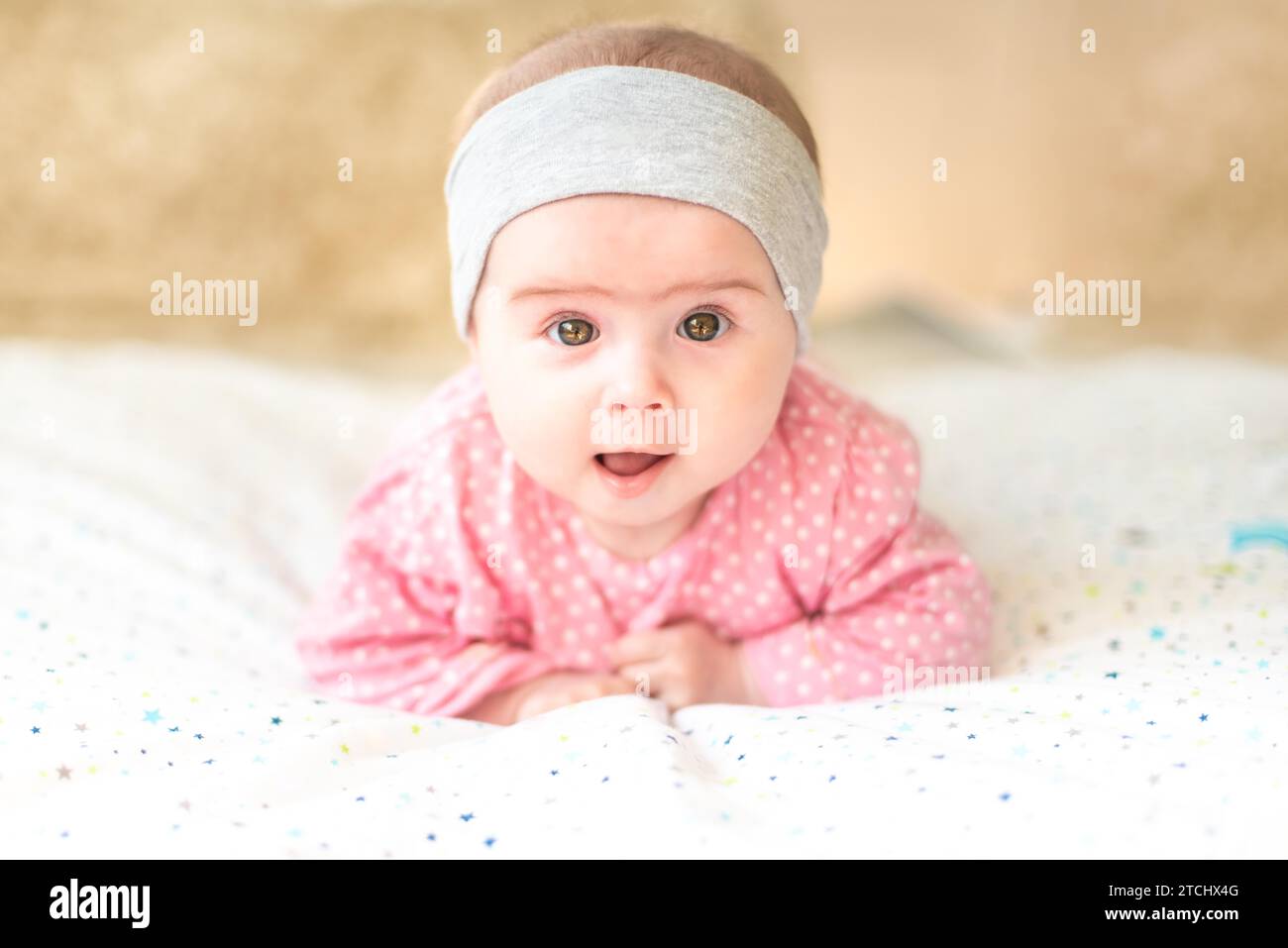 Adorable baby girl with grey headband looking towards camera and smiling. Health concept. 6 ...