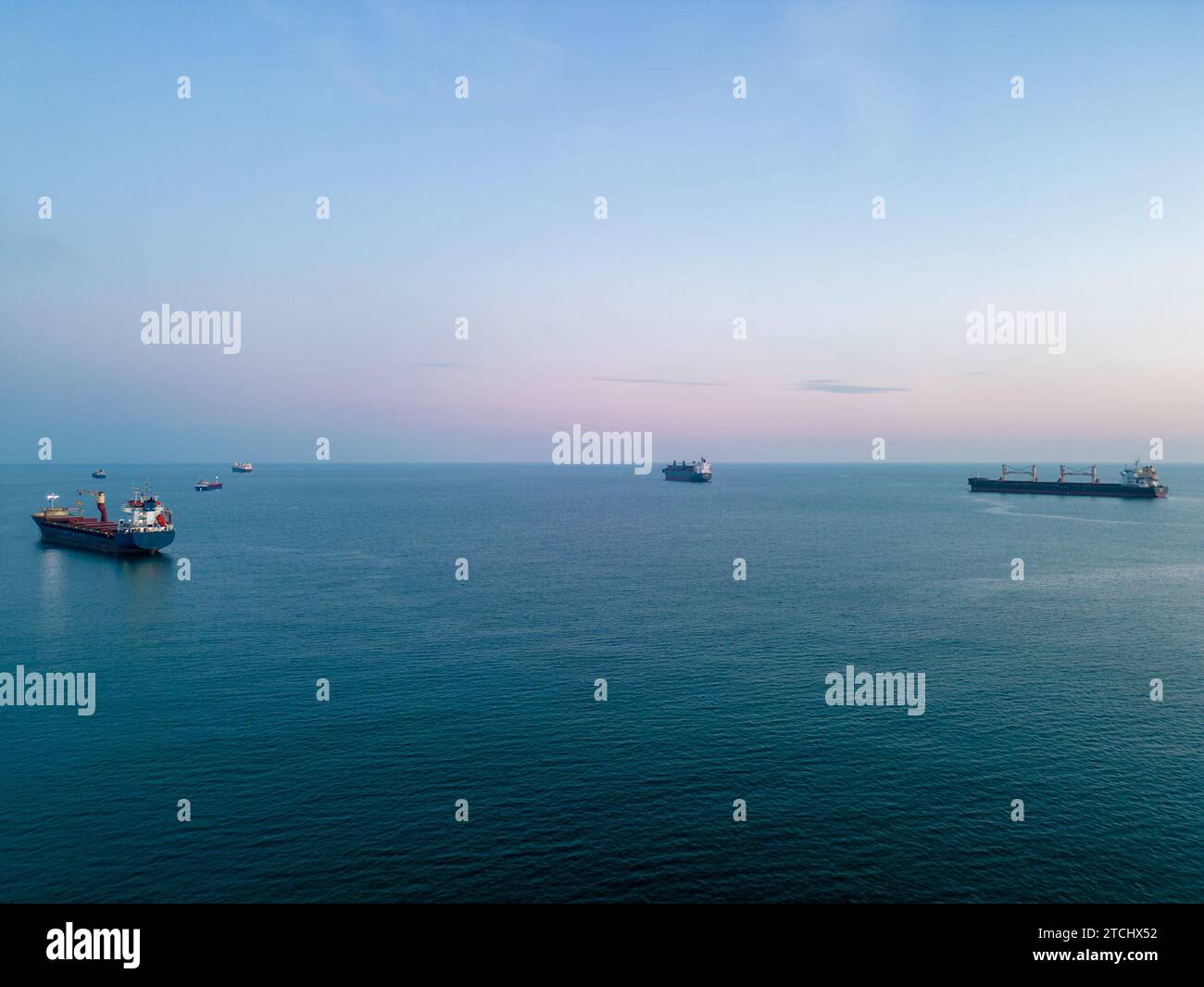 Several cargo ships in a sea bay are waiting in a queue to enter the ...