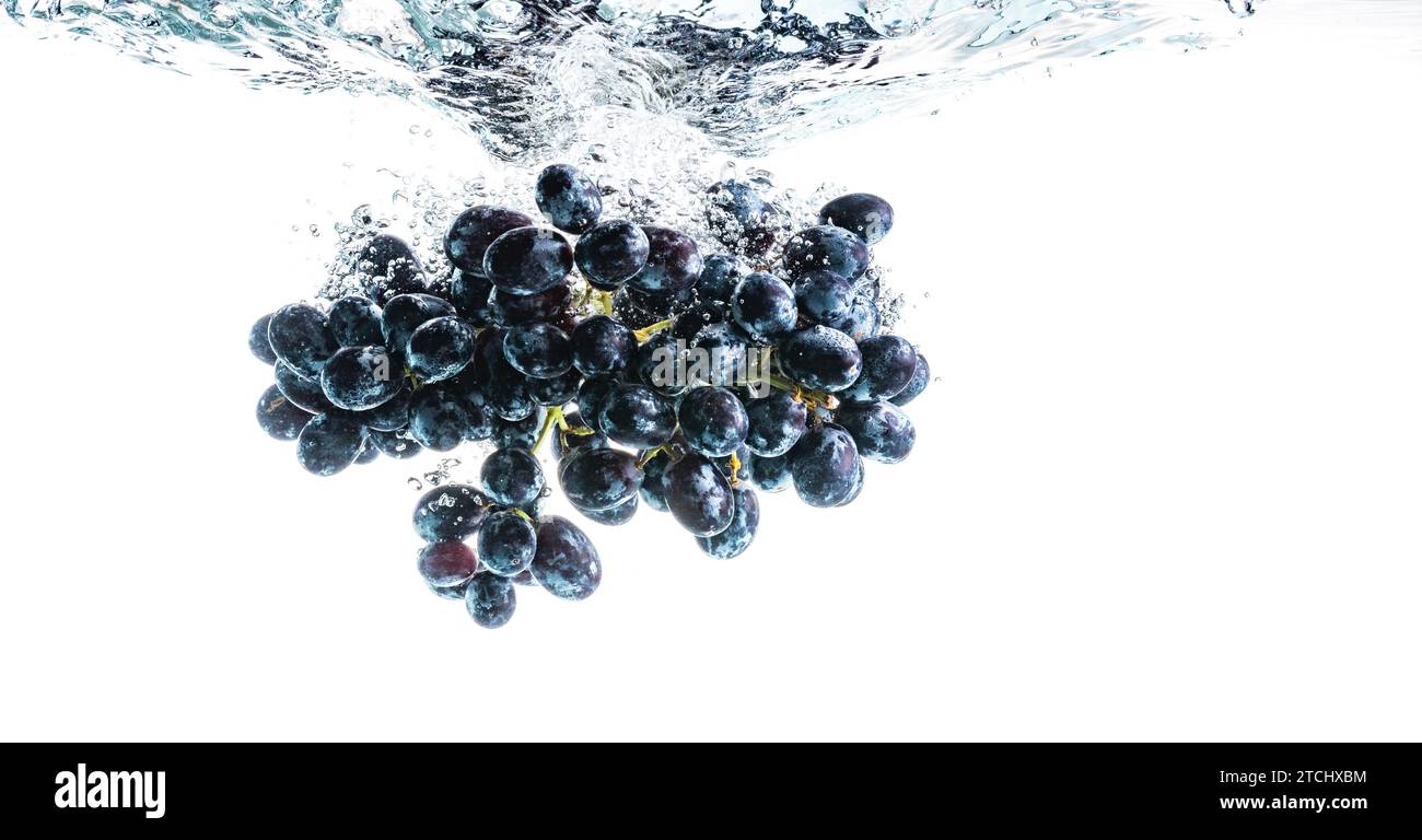 Bunch of red grapes splashing into crystal clear water on withe ...