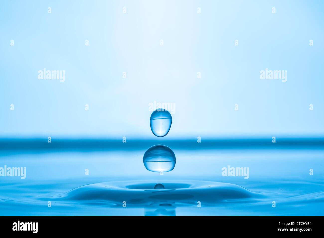 Water drop splashing into blue water surface. Health and purity concept ...