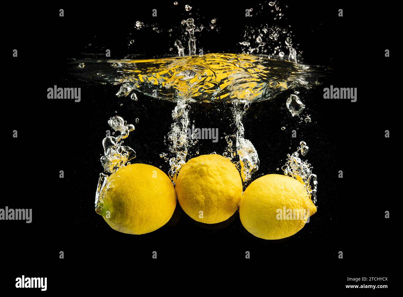 Fresh yellow lemons in water splash on black background with lots of ...