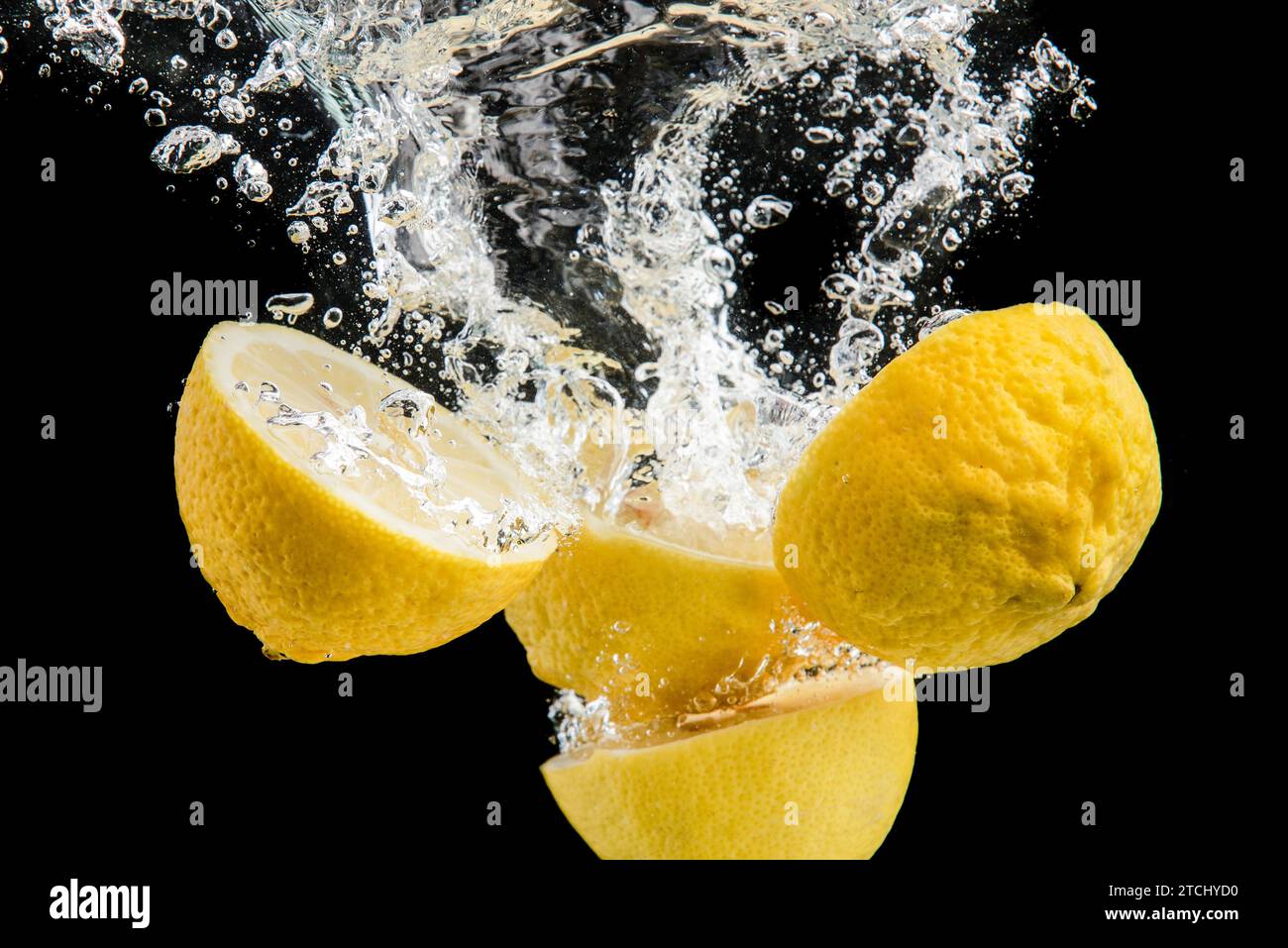 Fresh yellow lemons in water splash on black background with lots of ...