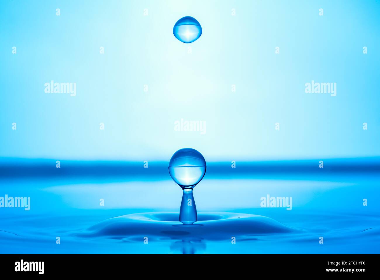 Water drop splashing into blue water surface. Health and purity concept ...