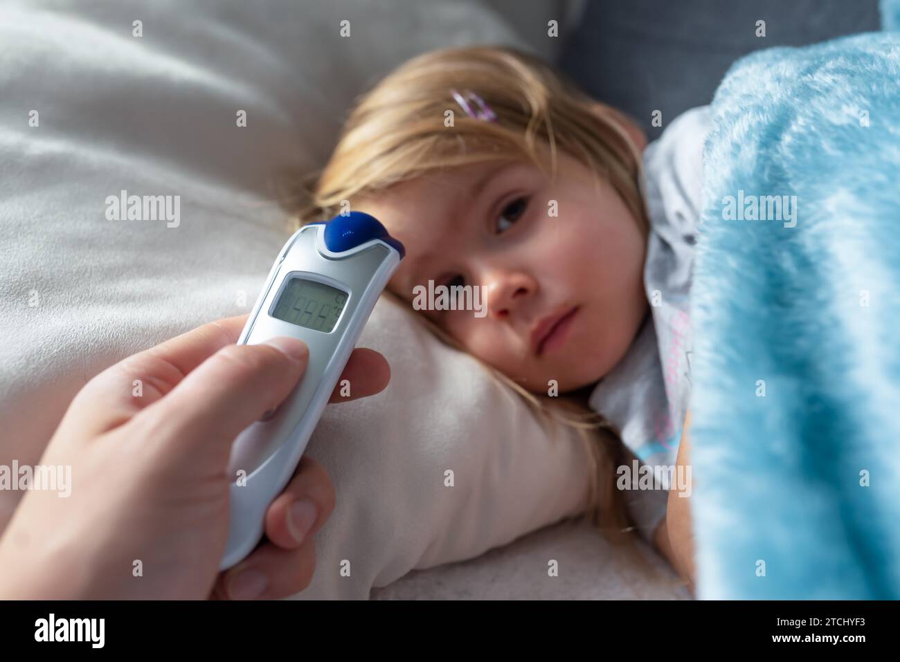 Mother takes temperature for her child with infrared thermometer at home, low-grade fever Mother ...