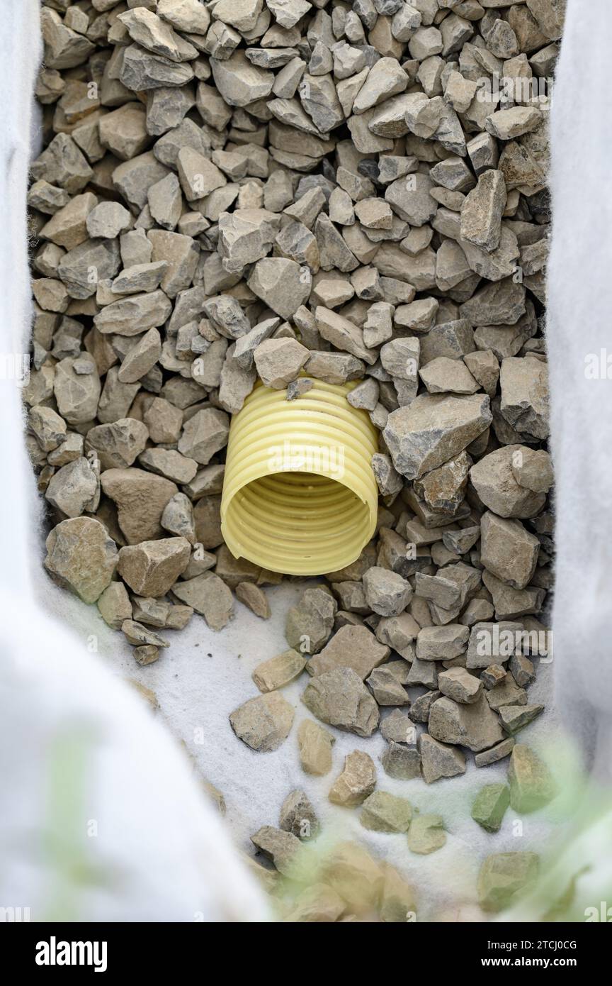 Yellow corrugated pipe with perforation in a trench with crushed stone ...