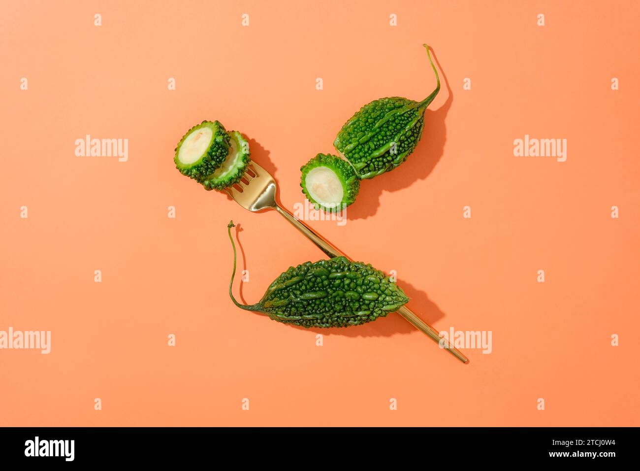 A metal fork and bitter melon on a red background. Bitter melon ...