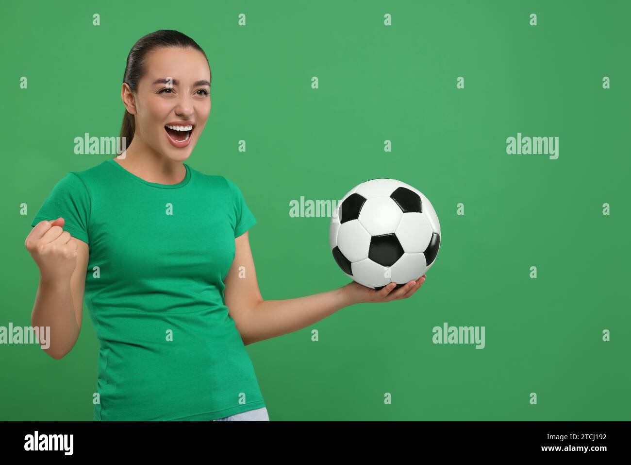 Happy fan with soccer ball celebrating on green background, space for ...