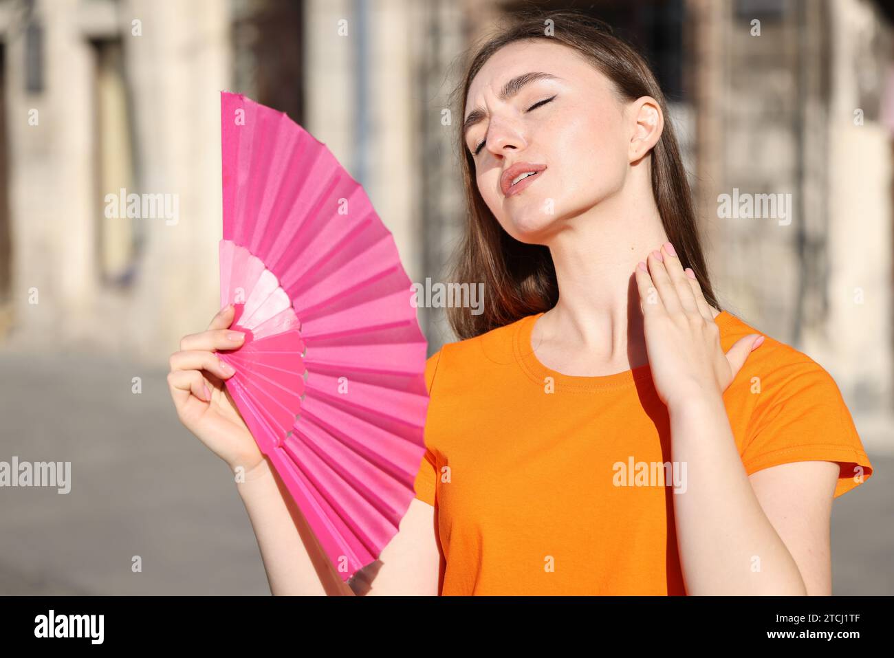 Woman with hand fan suffering from heat outdoors Stock Photo - Alamy
