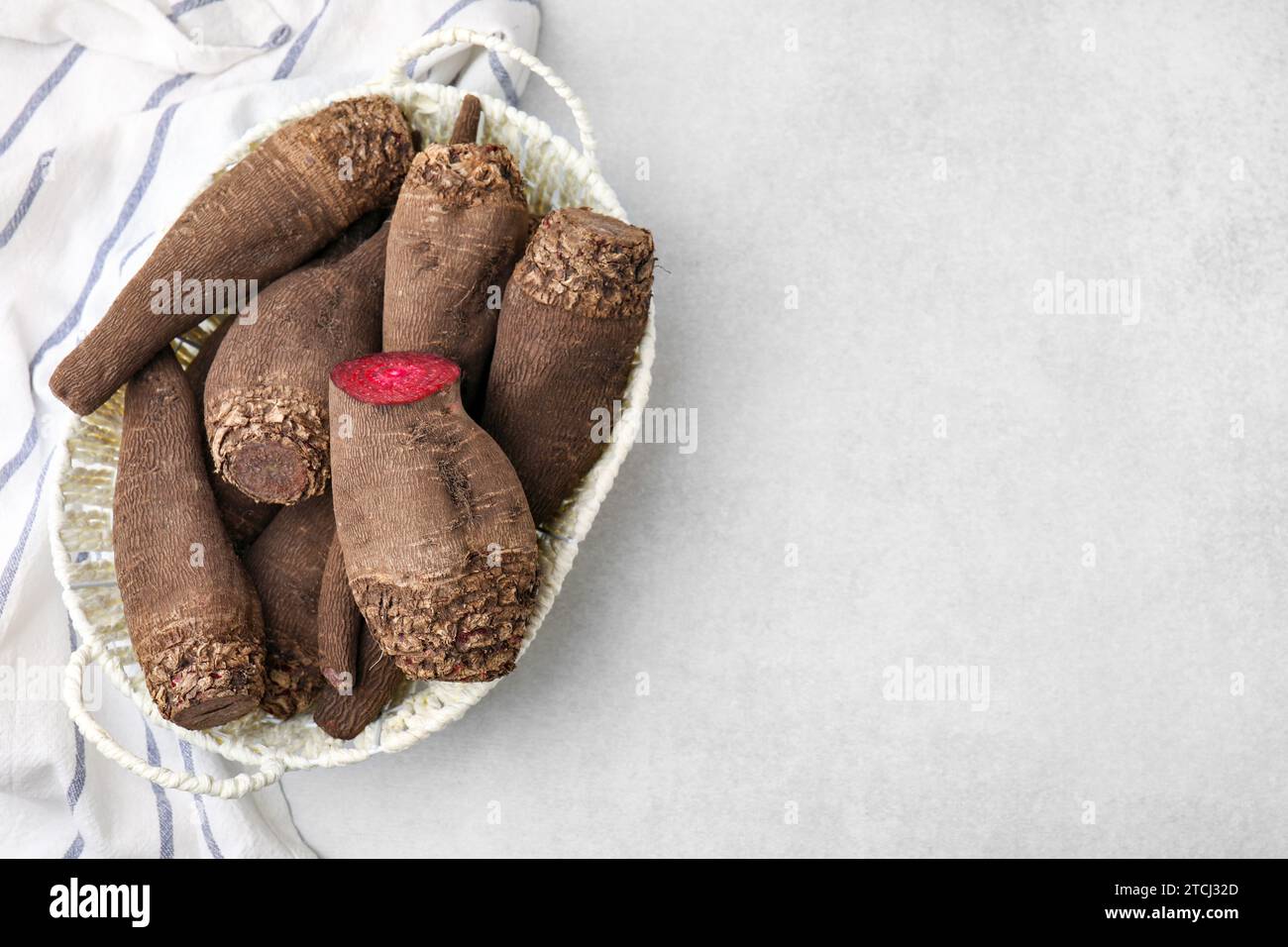 Whole and cut red beets in basket on light gray table, top view. Space ...