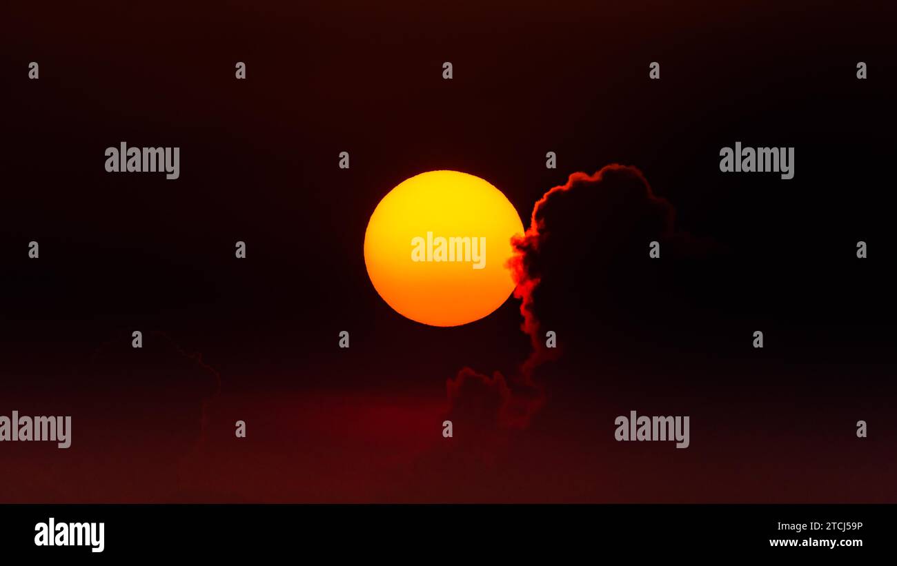 Orange, yellow Sun at sunset against red sky with back lit cloud Stock ...