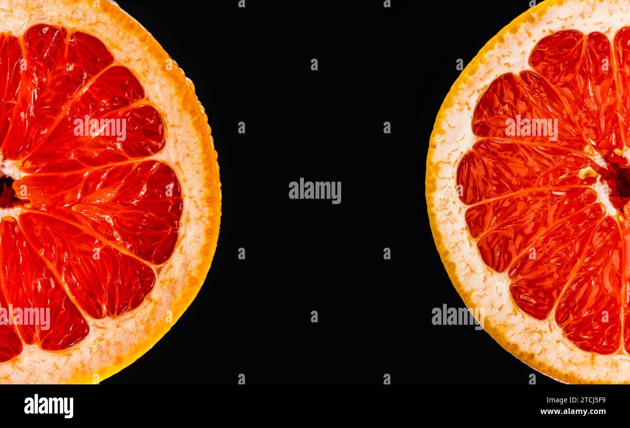 Fresh red grapefruit cut in half on black background. Negative space in ...