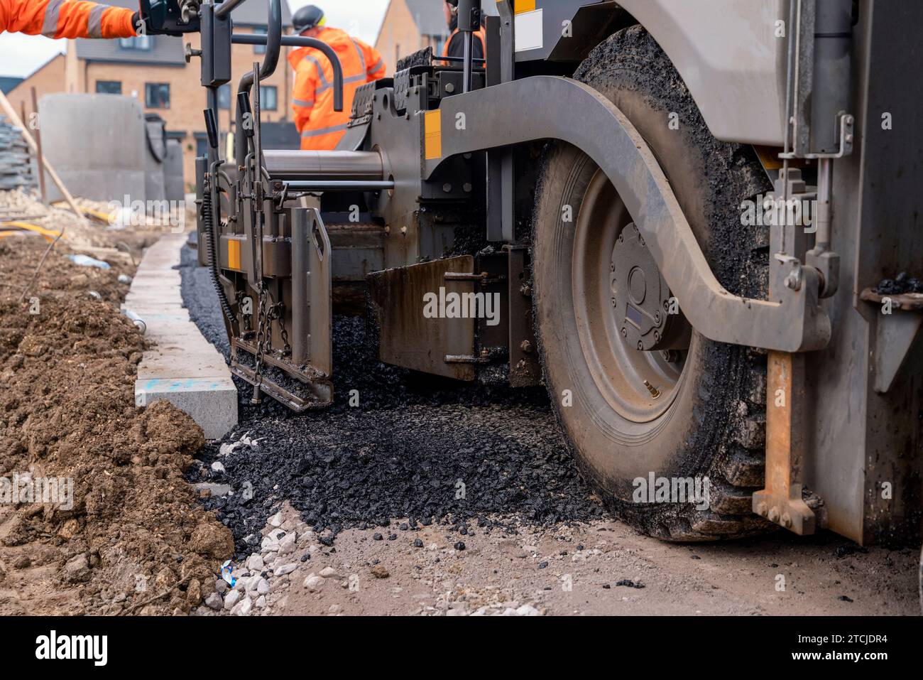 Asphalt paver filled with hot tarmac laying new road surface on new ...