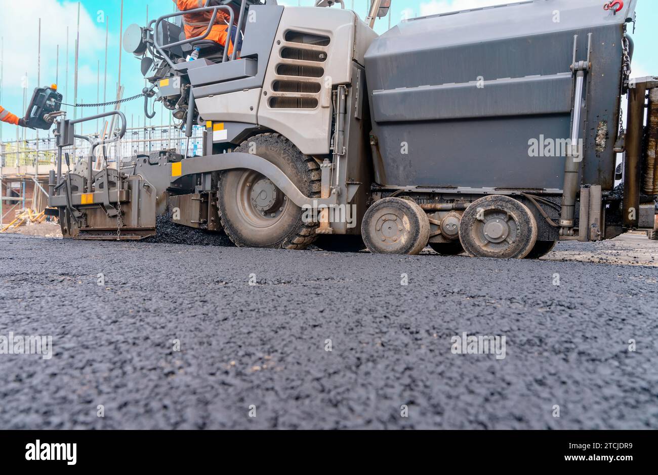 Asphalt paver filled with hot tarmac laying new road surface on new ...