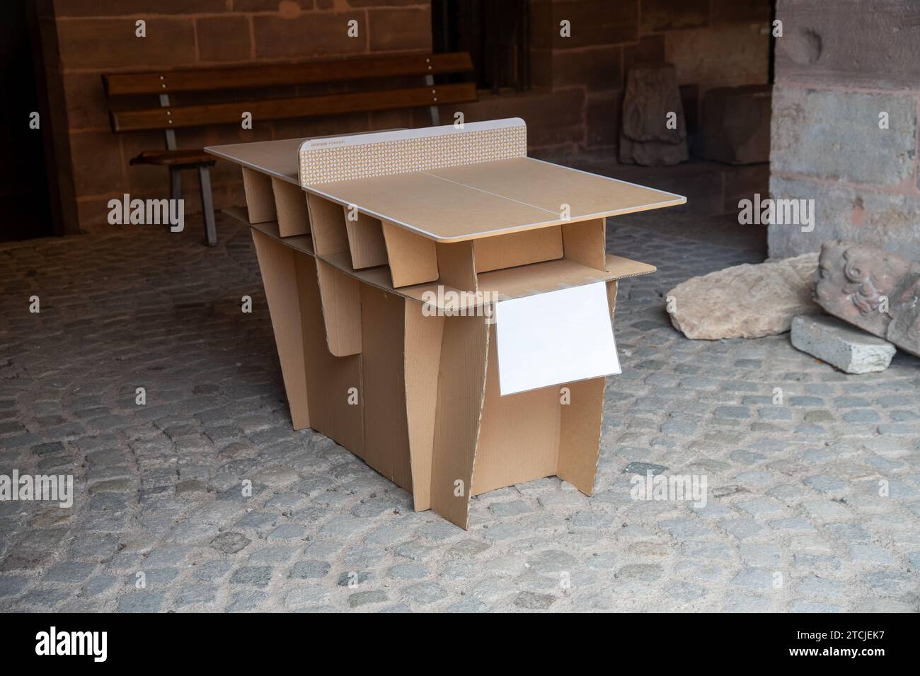 A table tennis table with a cardboard net, stable on a stone floor and ...