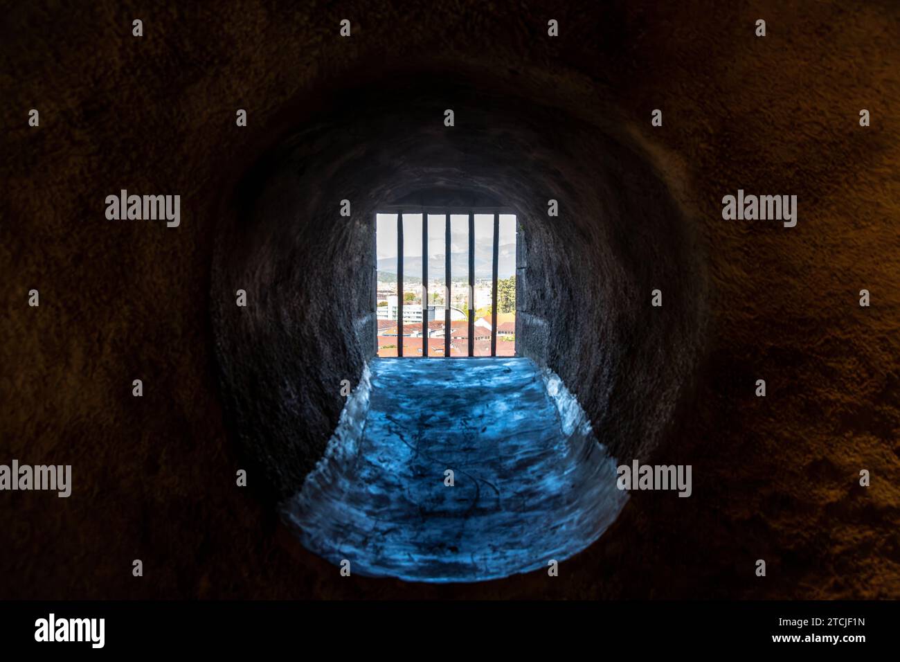 look through a barred window in a very thick wall of an old building ...