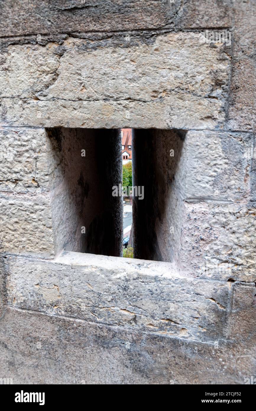 An embrasure in a thick old wall with a long, narrow vertical slit ...