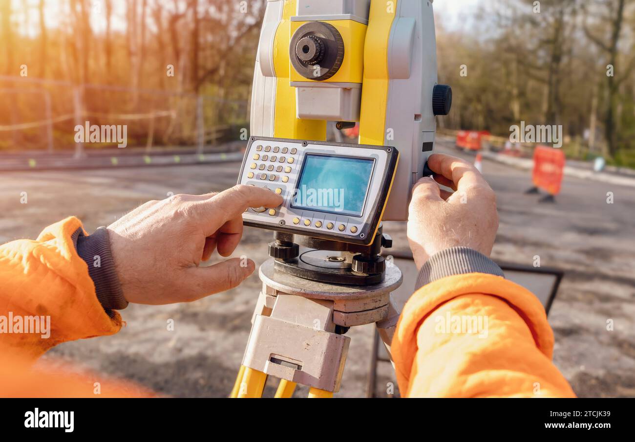 Site engineer operating his instrument during roadworks. Builder using ...
