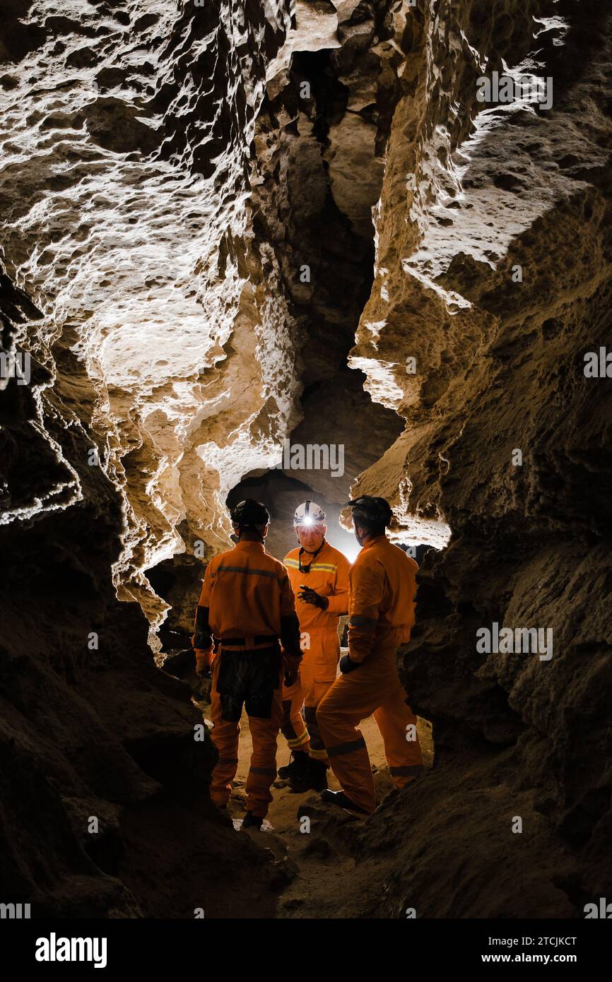 Three men, strong physique, explore the cave. Men dressed in special ...