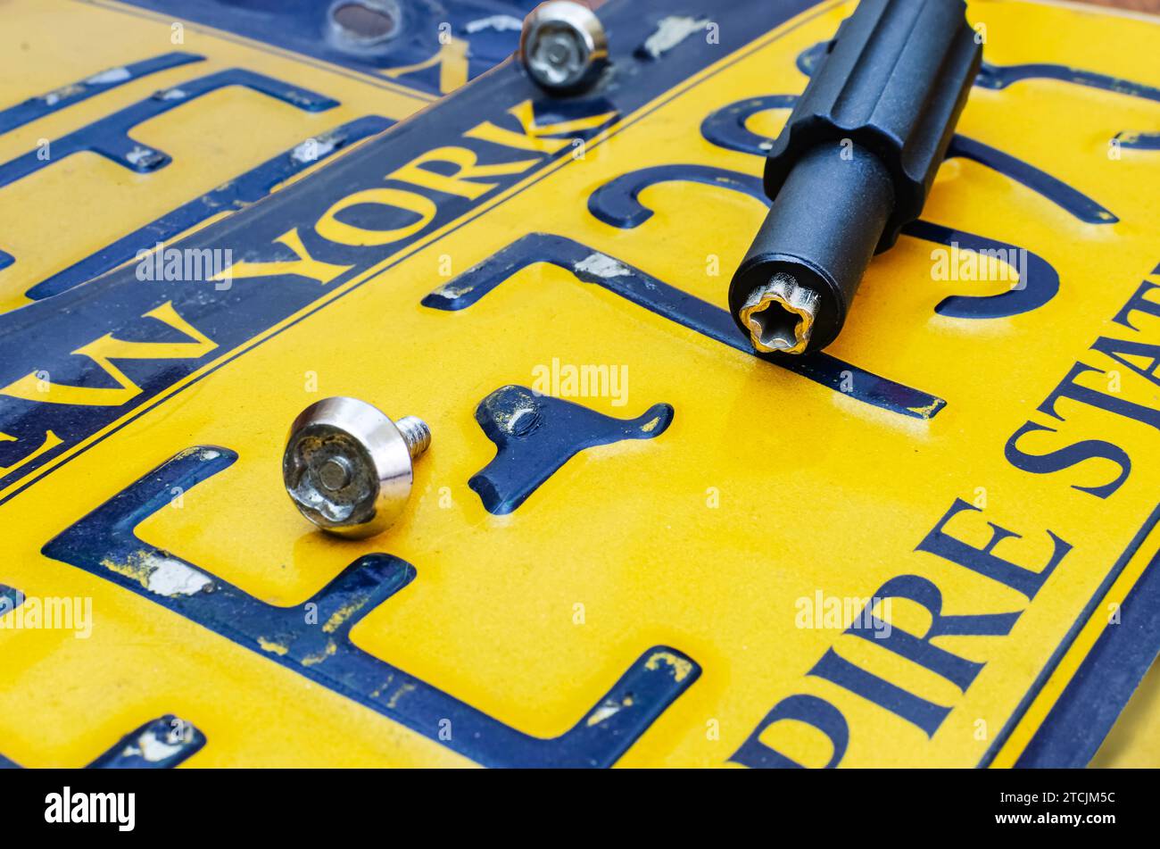Close-up of removing an old yellow car sign. Special screws and key ...