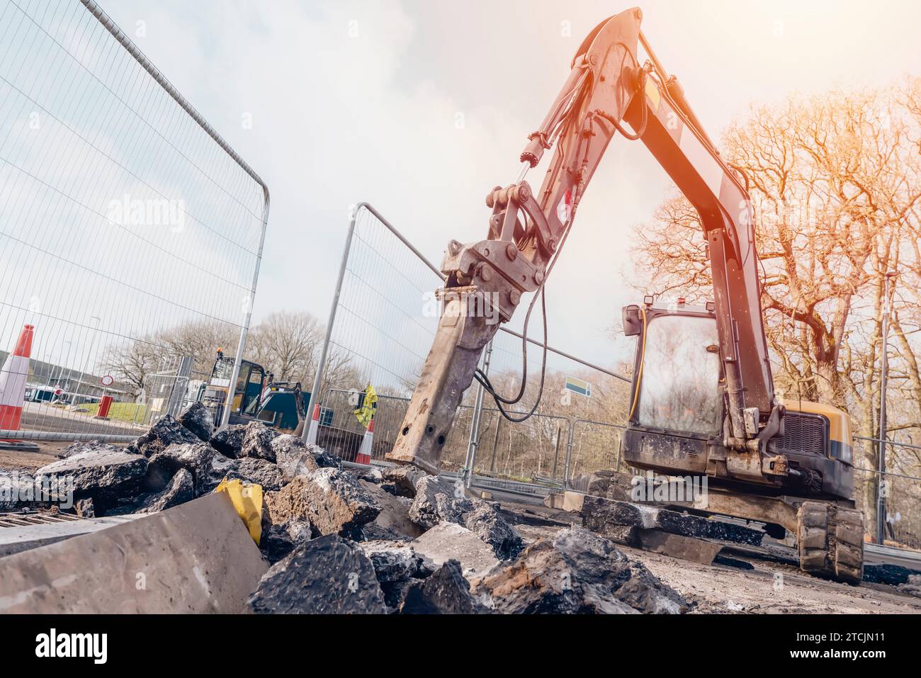 Excavator with hydraulic jack hammer breaking asphalt in preparation ...