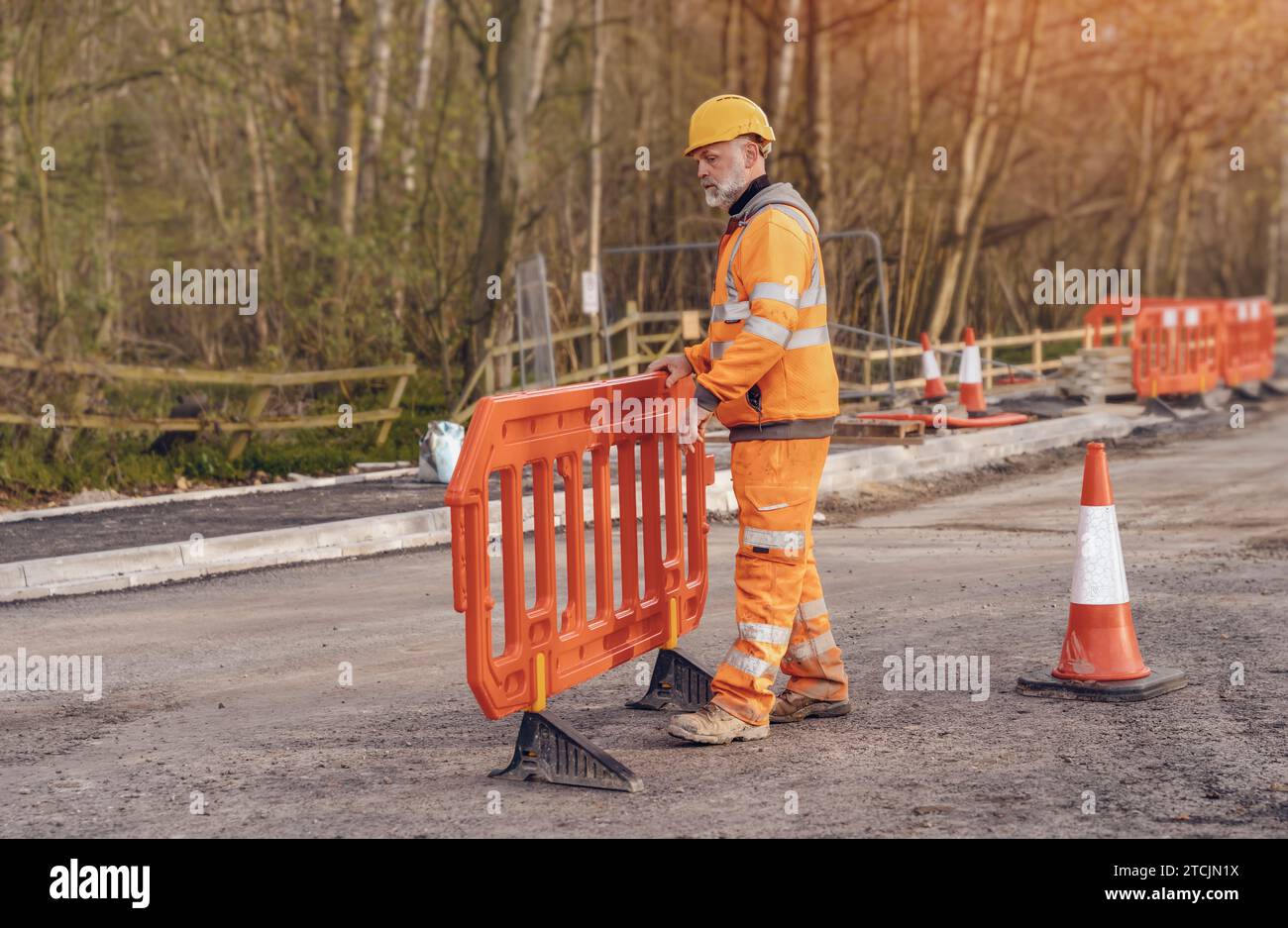 Builder placing safety barriers and red traffic cones during roadworks ...