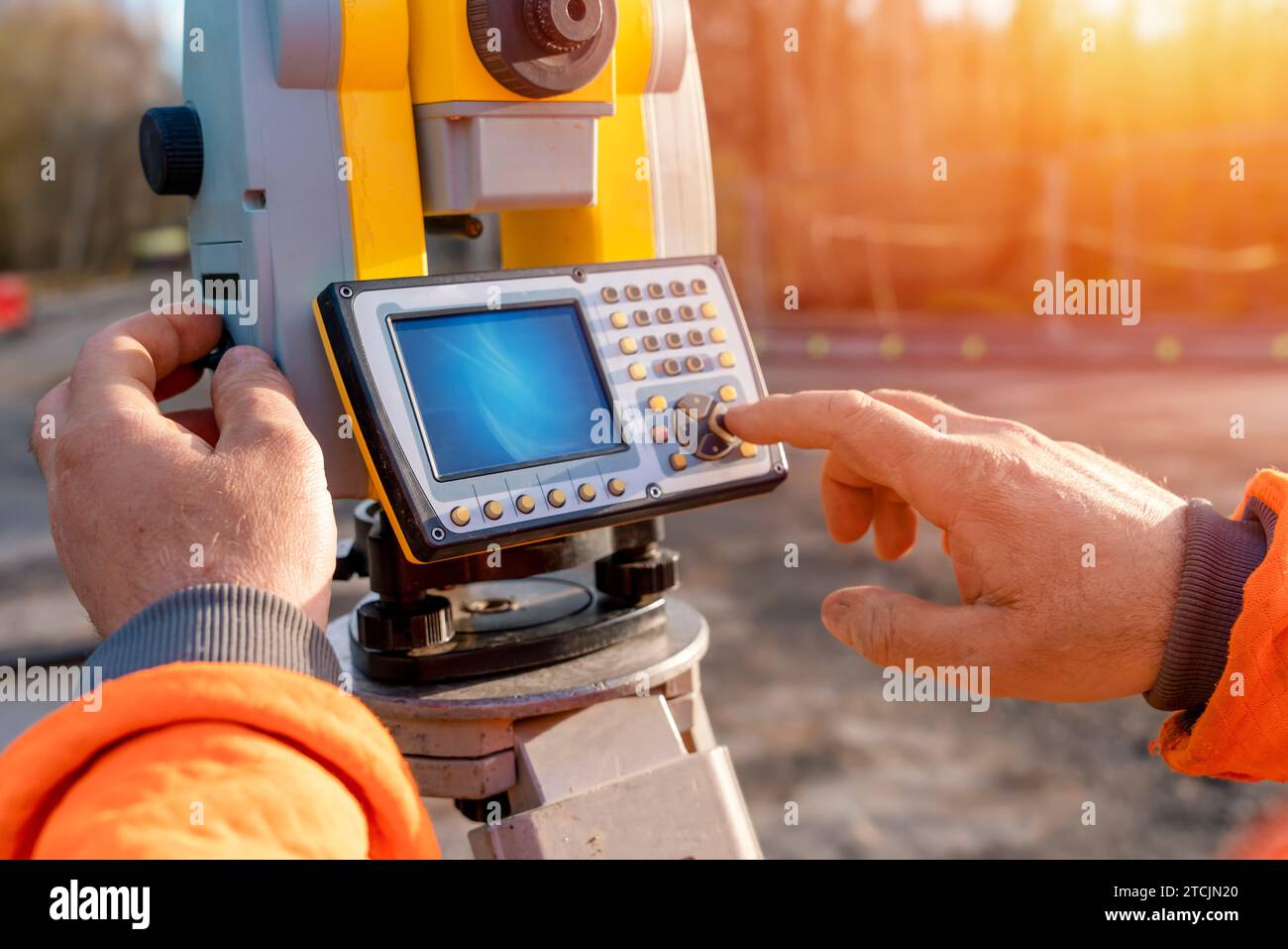 Site engineer operating his instrument during roadworks. Builder using ...
