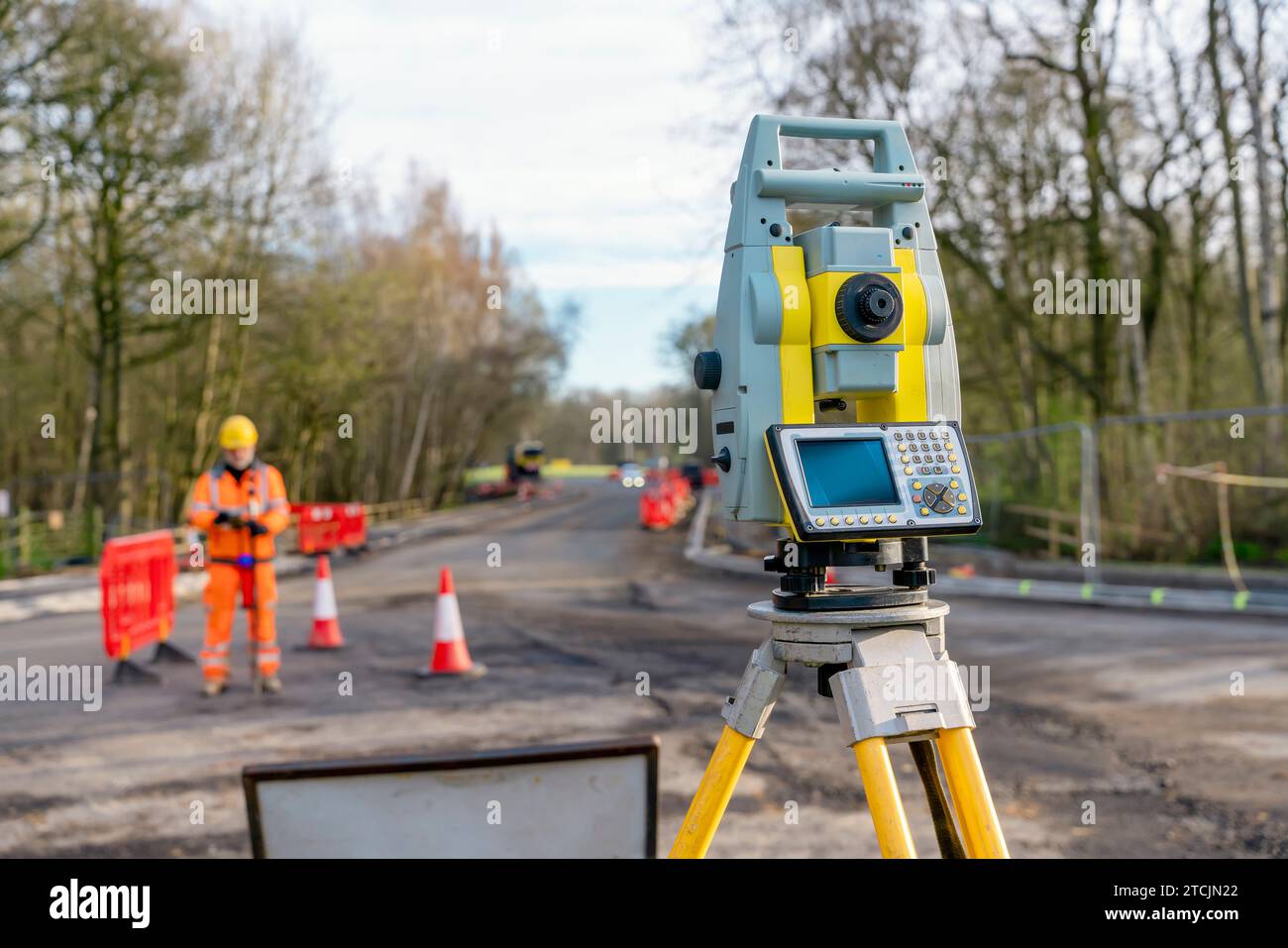 Site engineer operating his instrument during roadworks. Builder using total positioning station ...