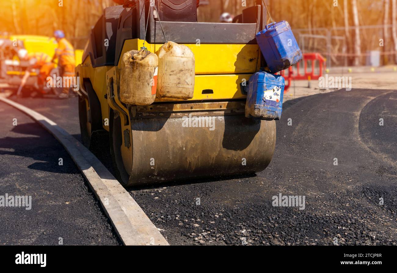 Asphalt paver filled with hot tarmac laying new road surface on new ...