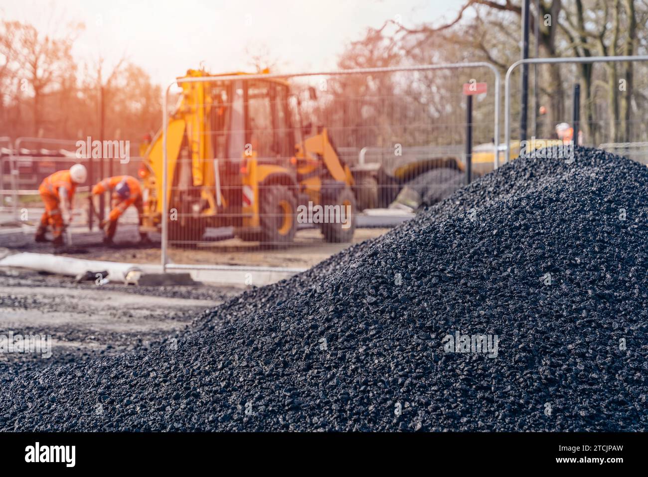 Asphalt paver filled with hot tarmac laying new road surface on new ...
