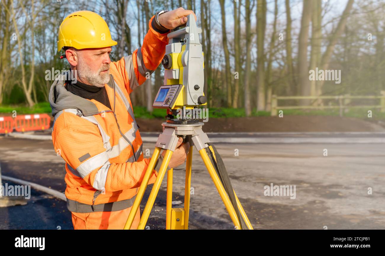 Site engineer operating his instrument during roadworks. Builder using ...