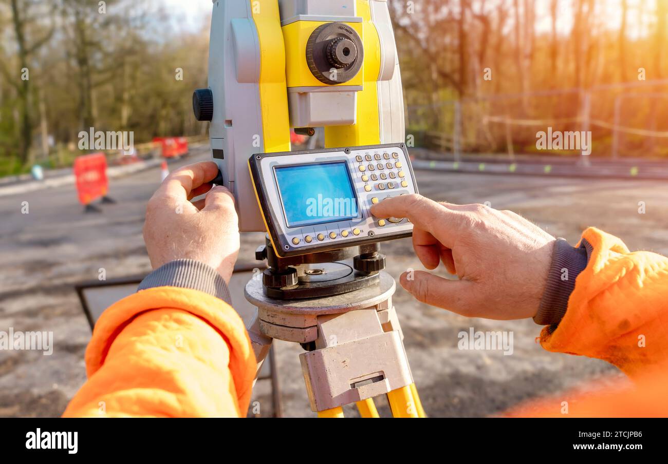 Site engineer operating his instrument during roadworks. Builder using ...