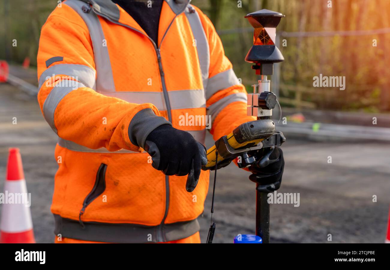 Site engineer operating his instrument during roadworks. Builder using ...