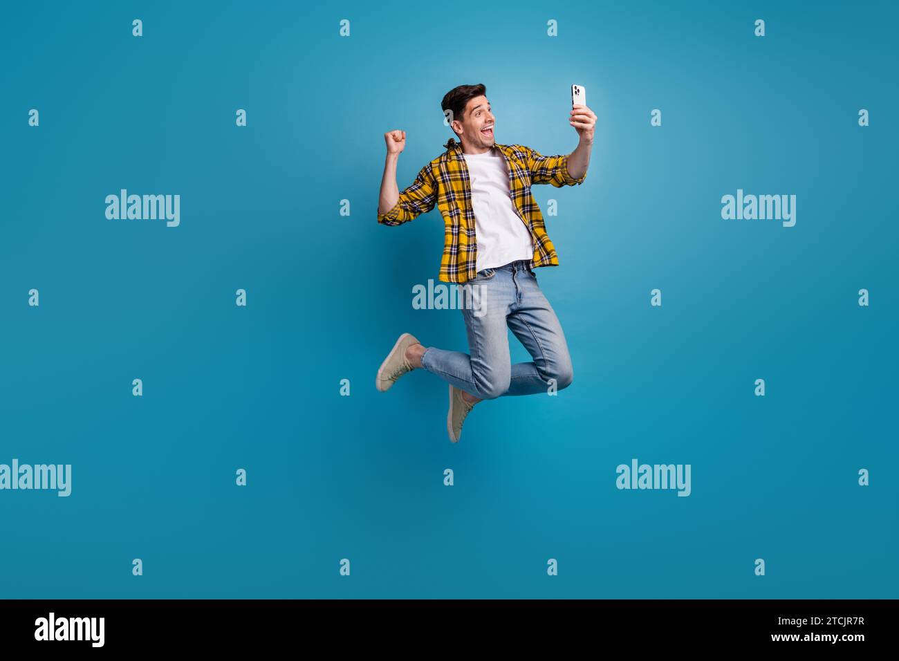 Full size body photo of funny man in air jumping with smartphone makes ...