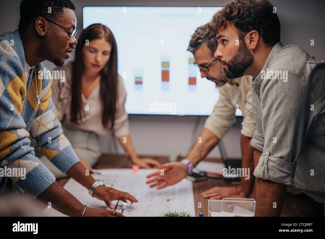 Multiracial business team discusses architectural blueprints, fostering ...