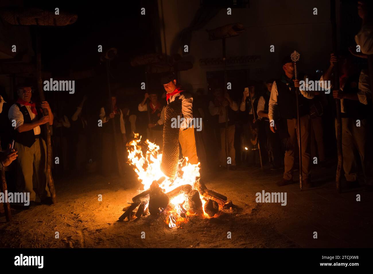 A villager Is seen lighting a torch on a bonfire outside a chapel as he ...