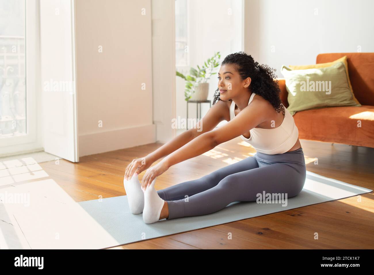 woman stretching on mat performing seated toe touch exercises indoor ...