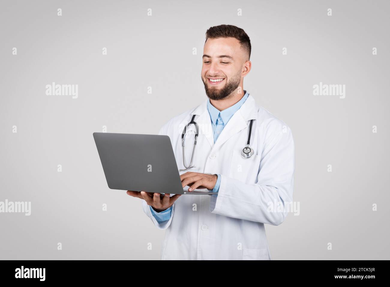 Smiling doctor using a laptop, technology in healthcare Stock Photo - Alamy