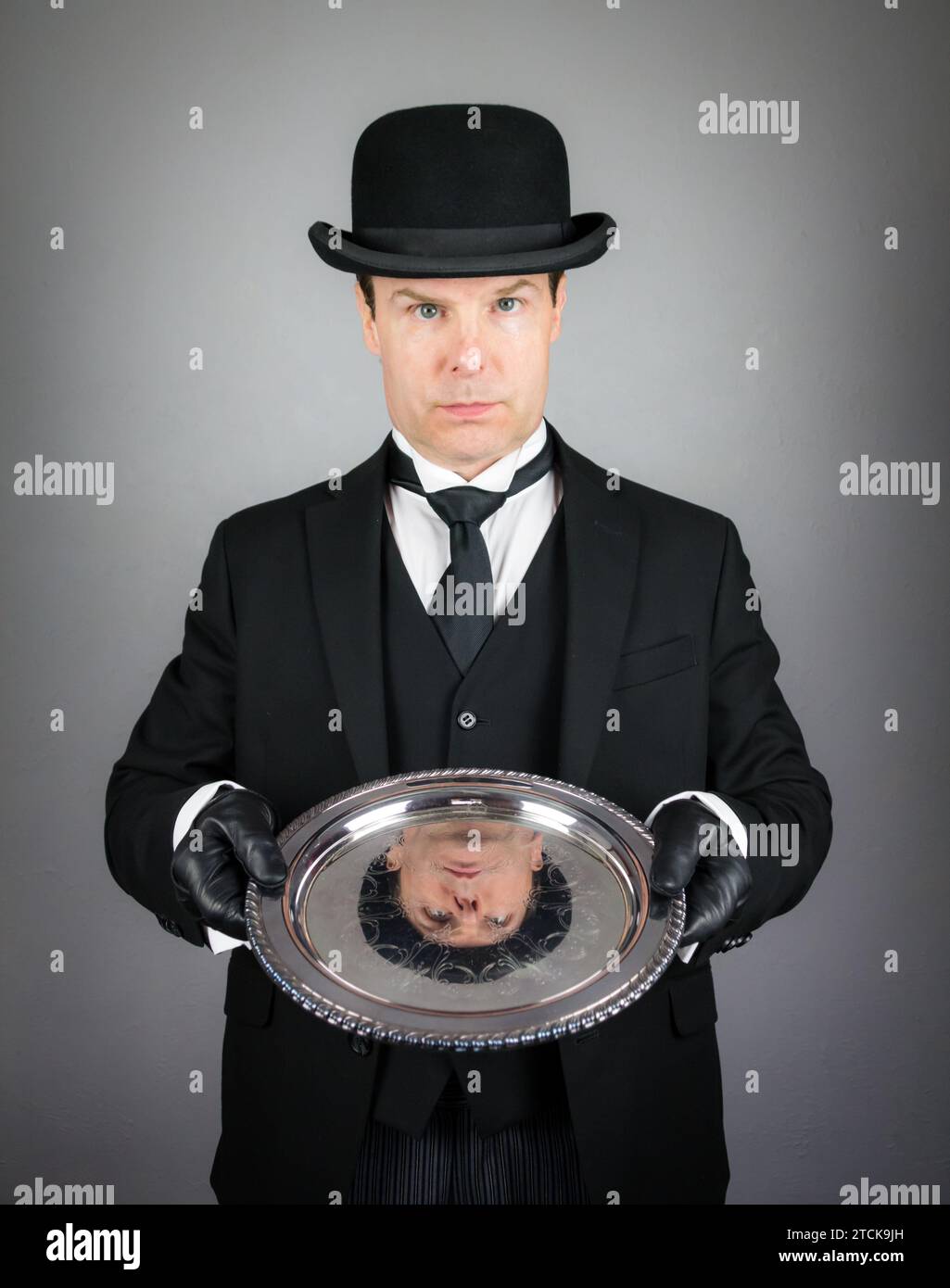 Somber British Butler in Dark Suit and Bowler Hat Holding Silver ...