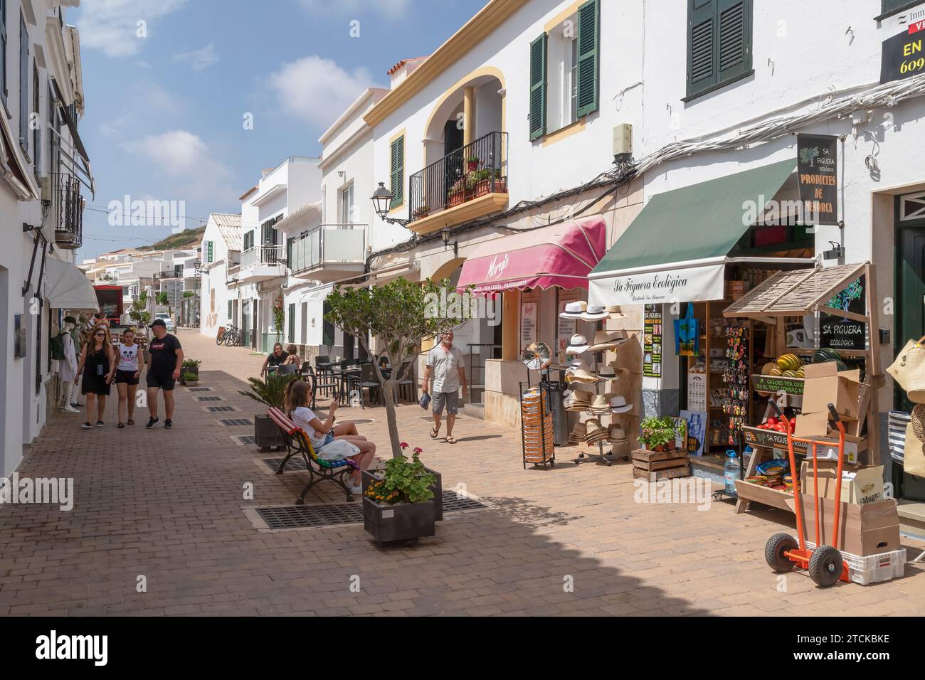 Tourists walk through a narrow cozy street with restaurants and shops ...