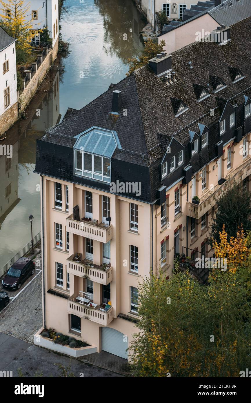 Three-story building with pink facade and dark roof on riverbank Stock ...
