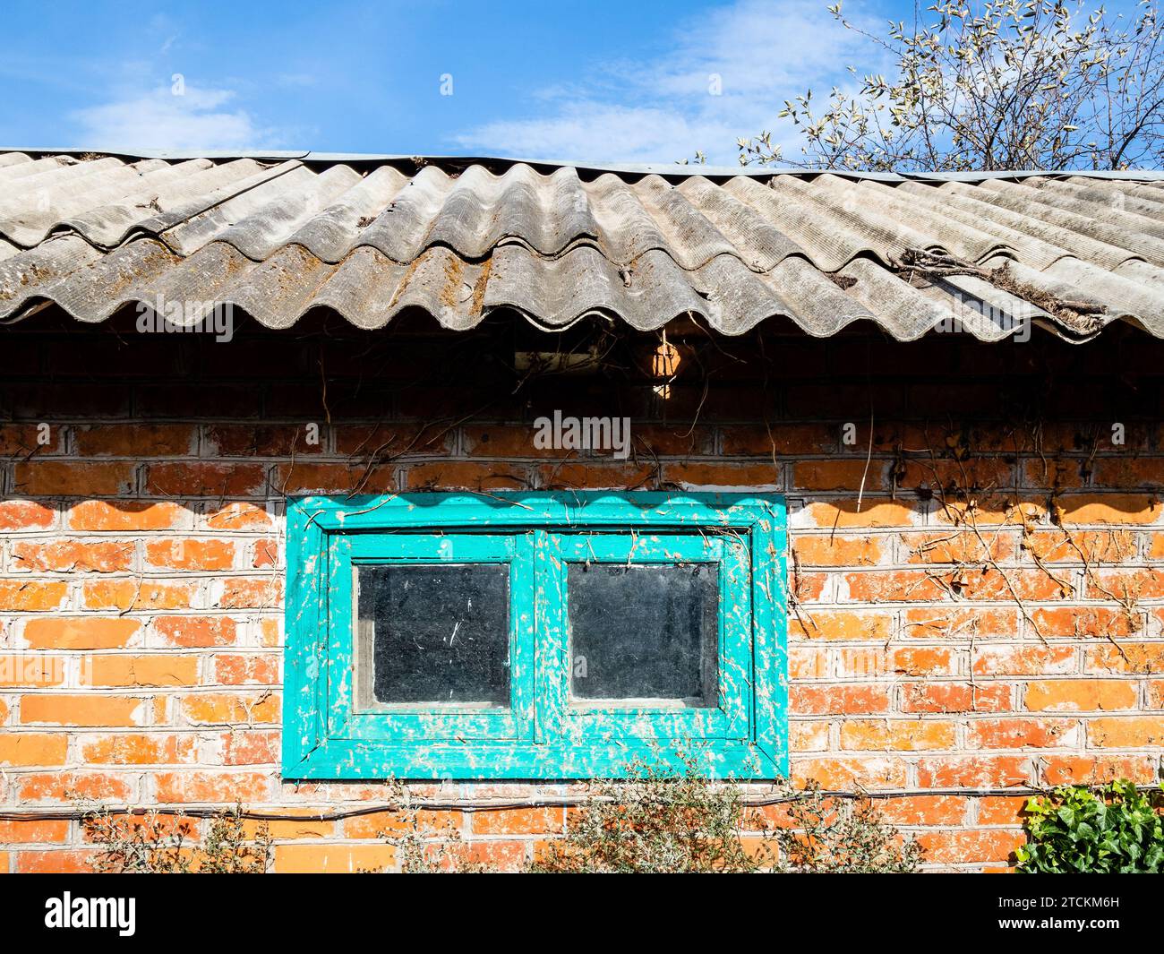 wall of rustic brick barn with dirty small window in green wooden frame ...