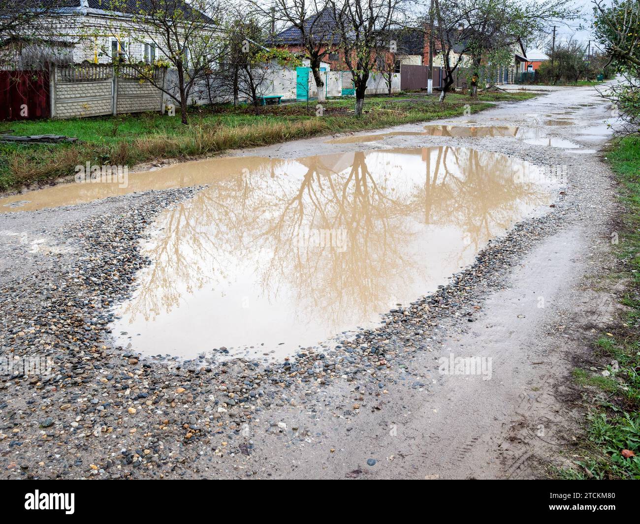 large dirty rain puddle on road in village on autumn day Stock Photo ...