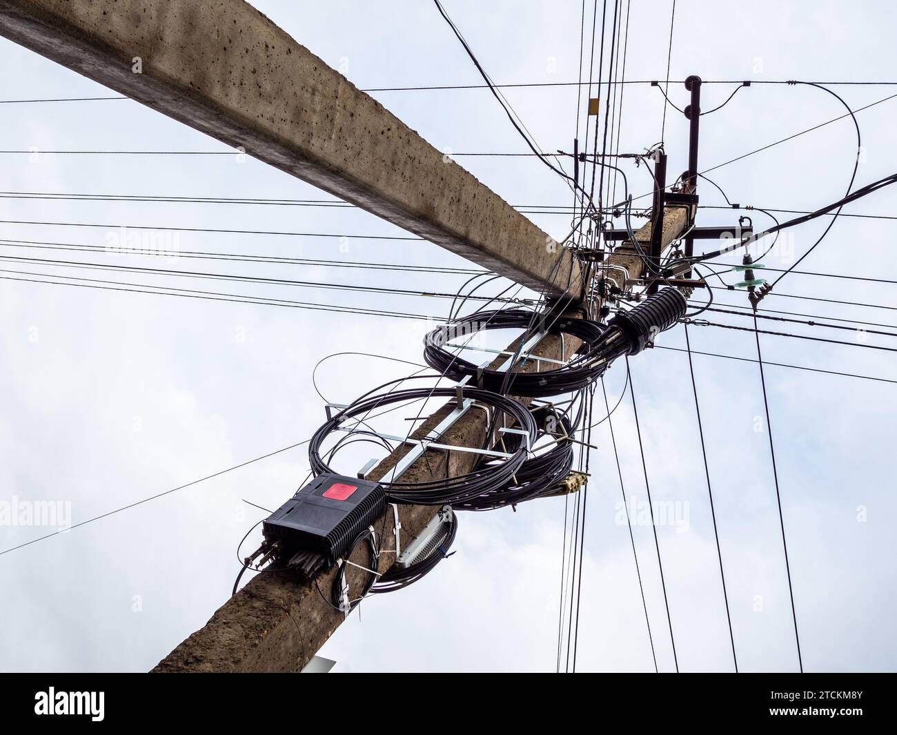 bottom view of concrete power line pole with lot of wires in village ...