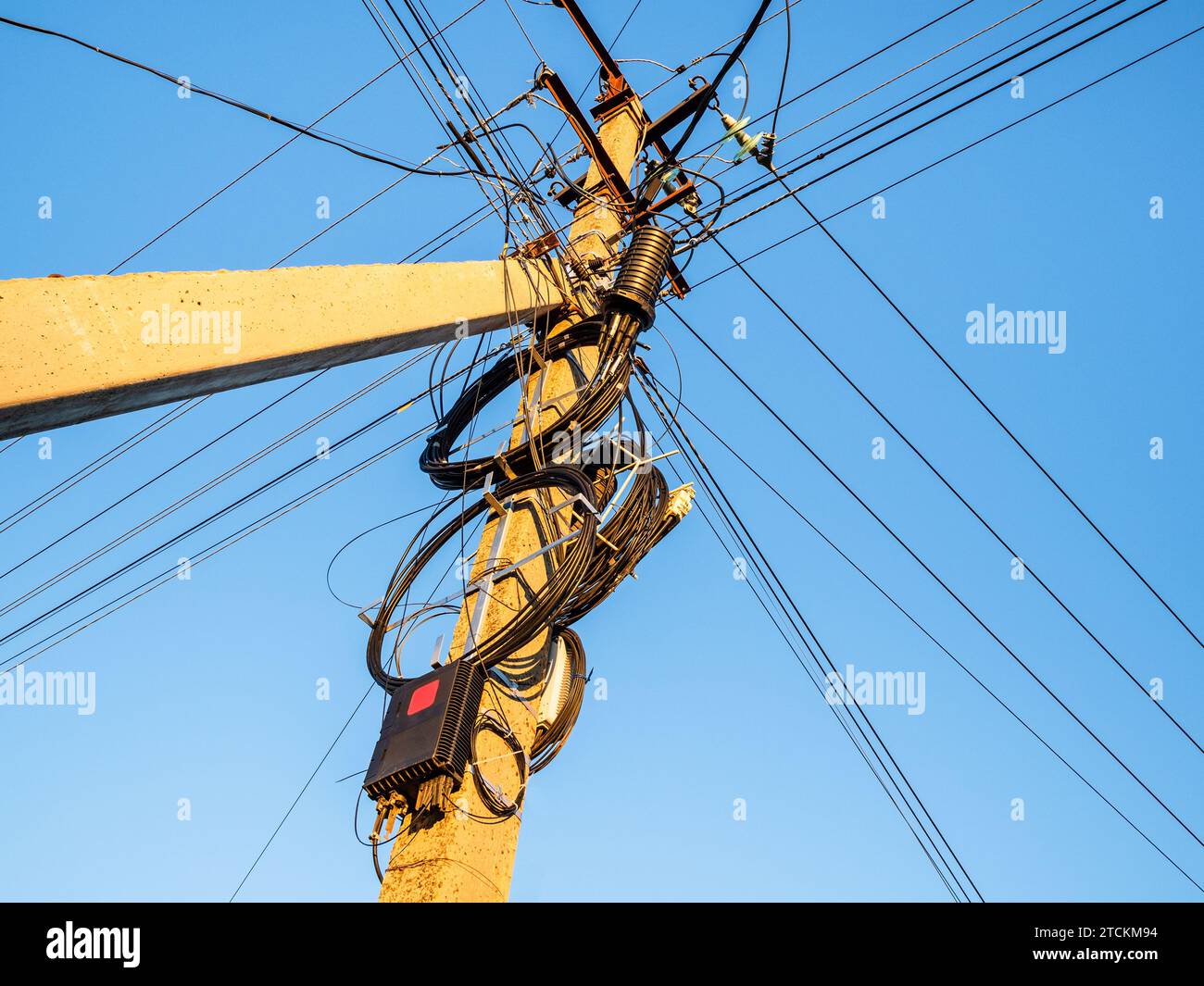 bottom view of concrete power line pole with lot of wires illuminated ...