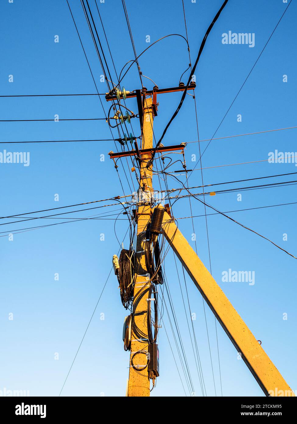 concrete power line pole with lot of wires illuminated by sun in ...