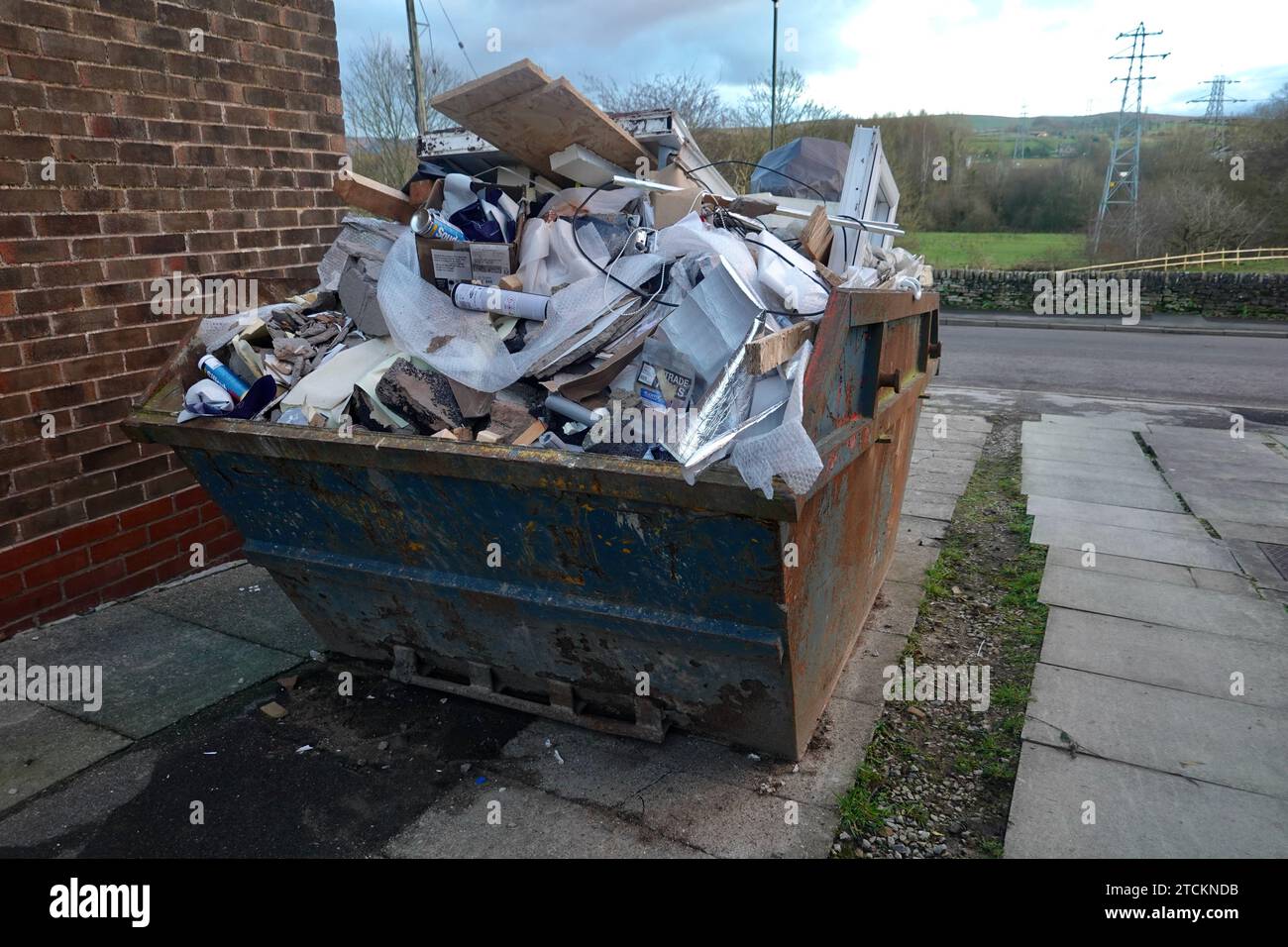 An overloaded skip on a drive outside a house Stock Photo - Alamy