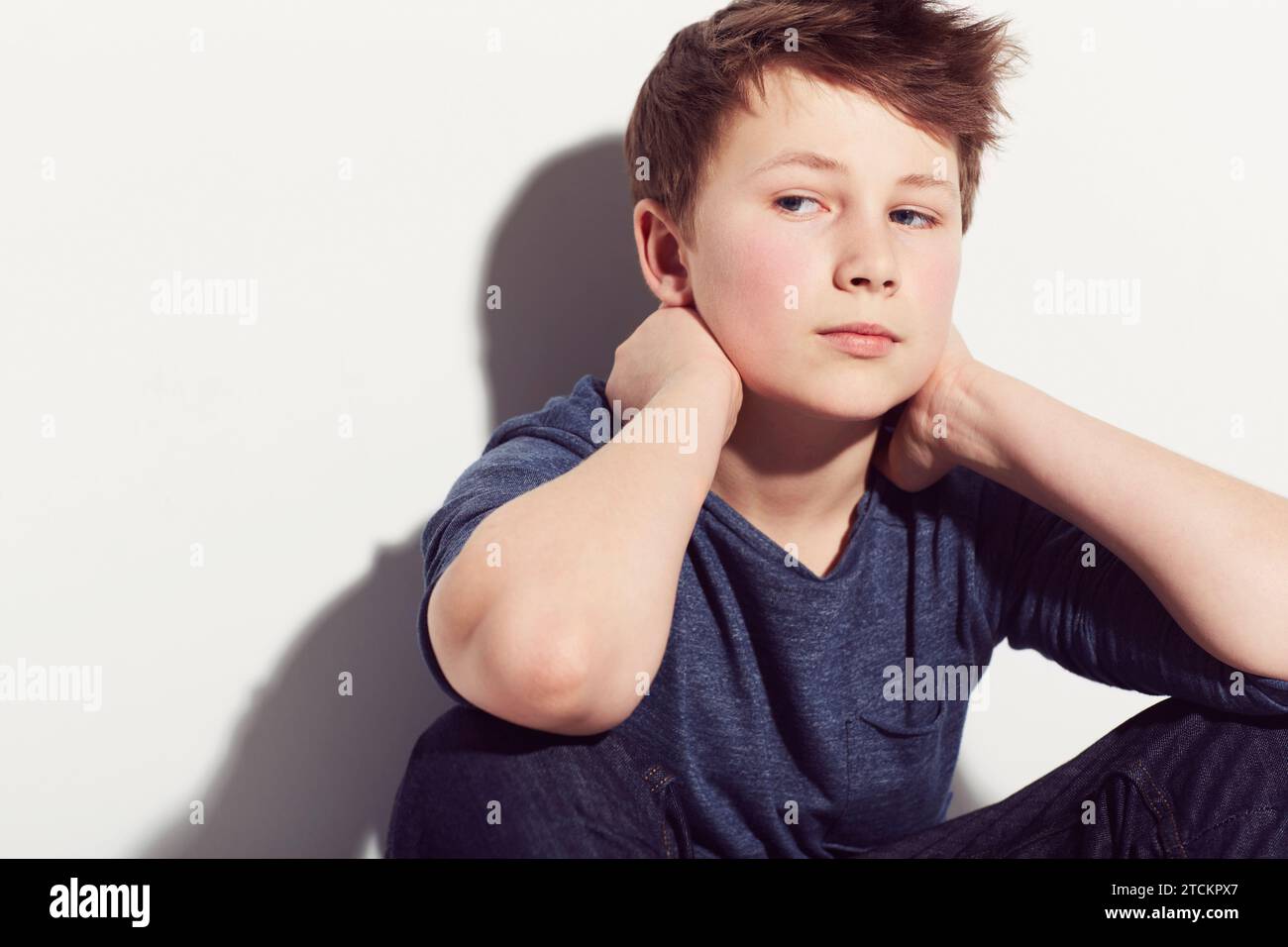 Serious, teenager and boy thinking in studio sitting in white ...