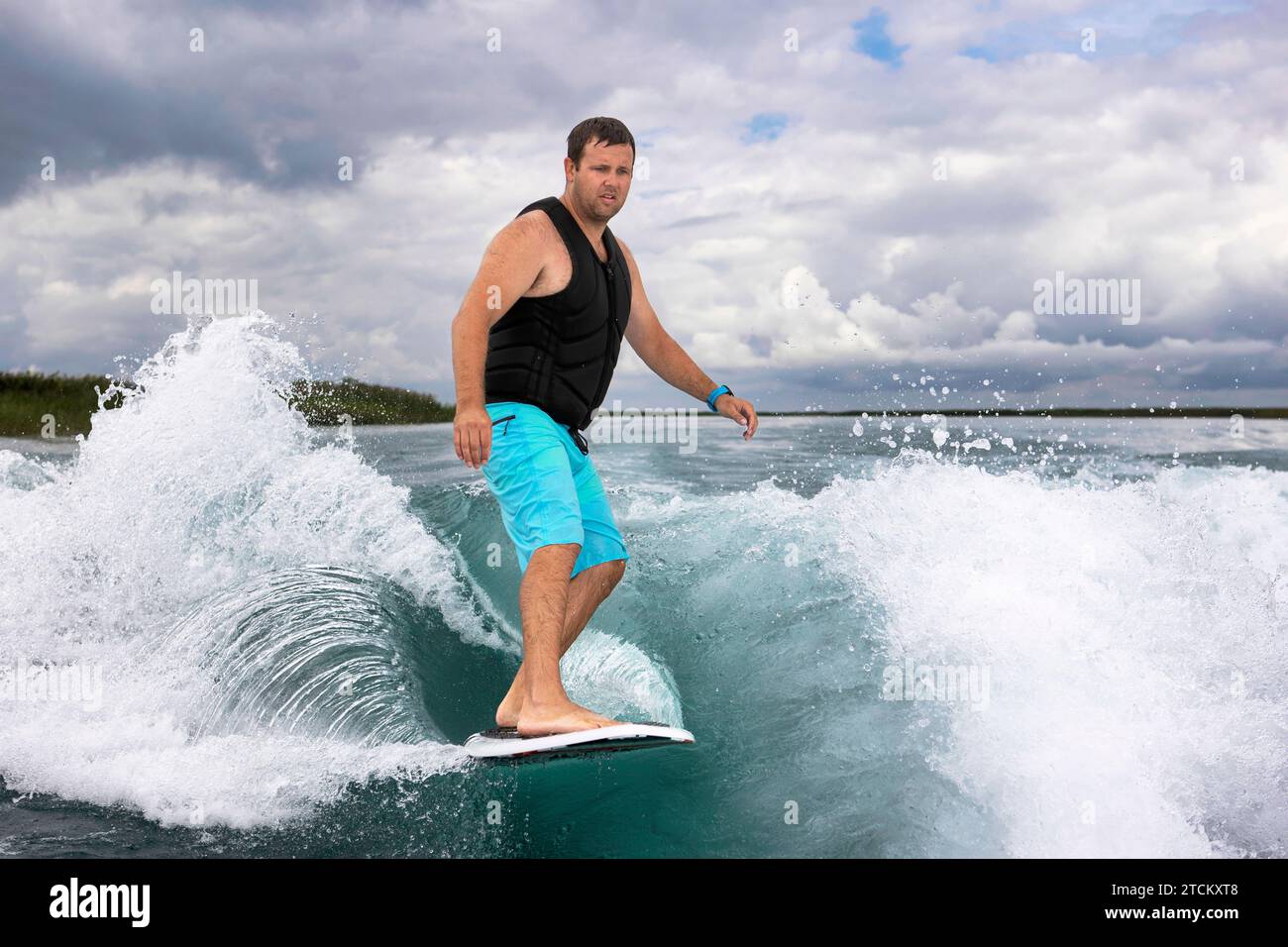 A man riding a surfboard on a boat wake Stock Photo - Alamy